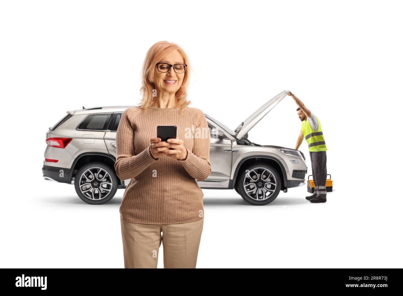 Road assistance worker fixing a SUV and woman using a smartphone ...