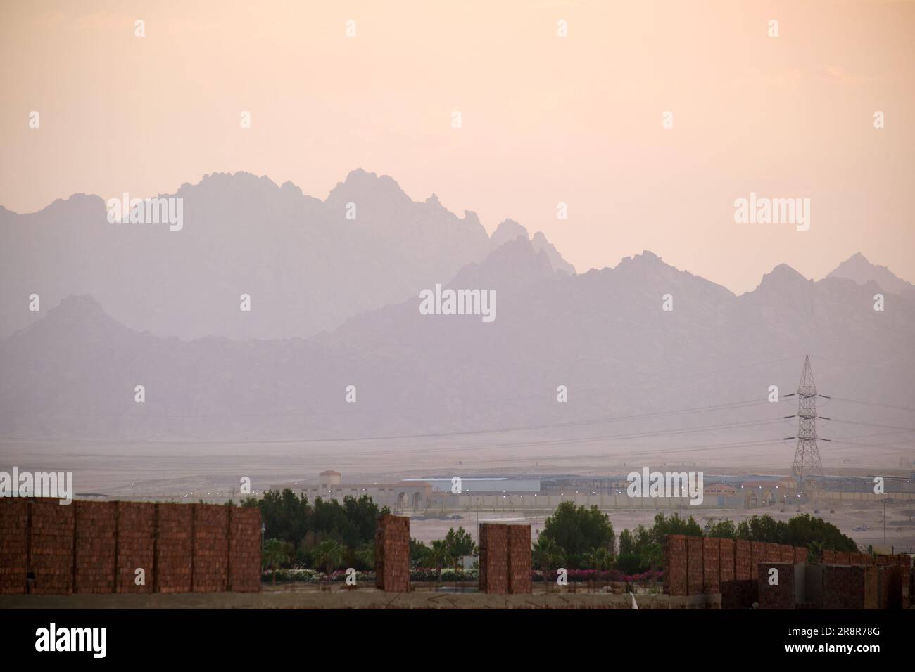 Sunset landscape with remote hotel complex against dark mountain peaks ...