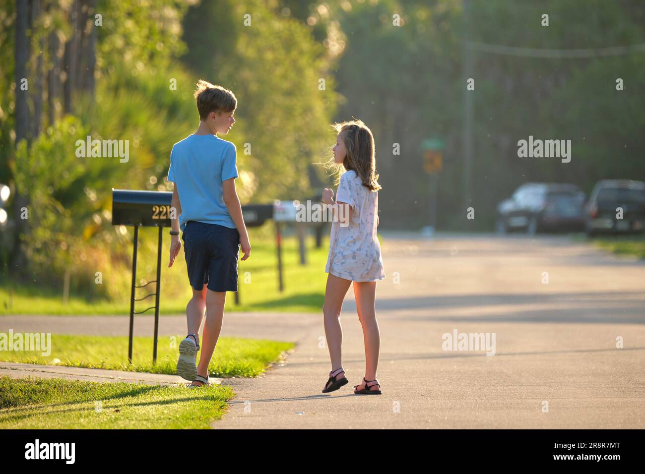 Two young teenage children, girl and boy standing and talking together ...