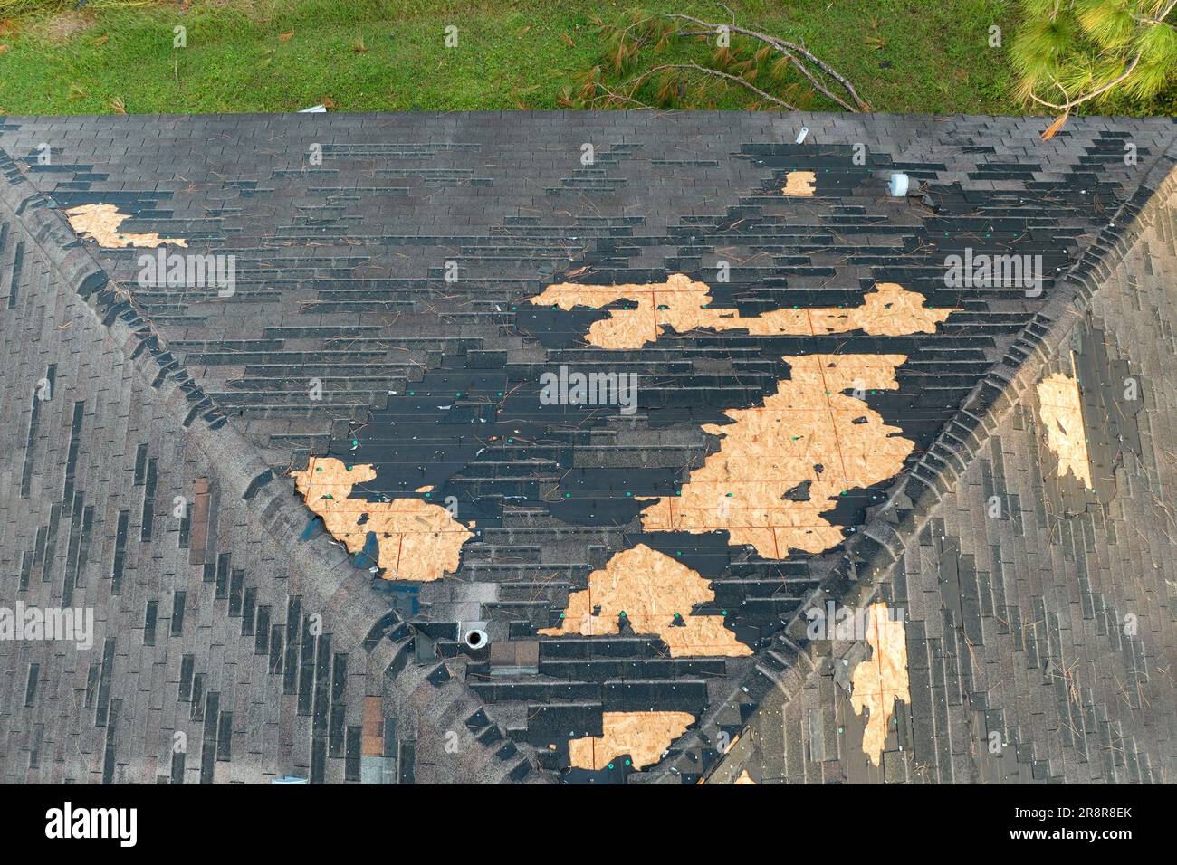 Wind damaged house roof with missing asphalt shingles after hurricane ...