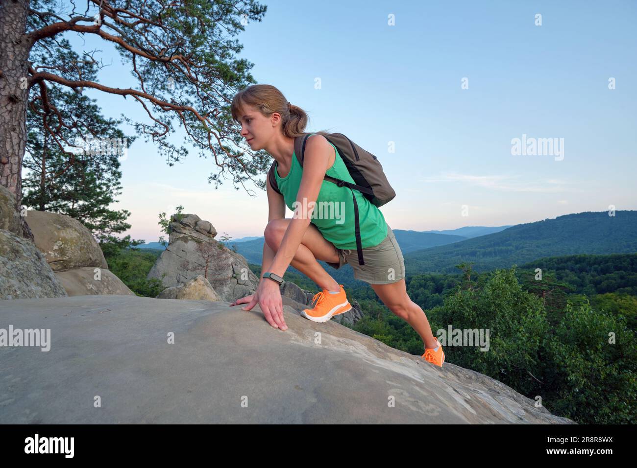 Young woman climbing alone on rocky mountain path. Female hiker ...