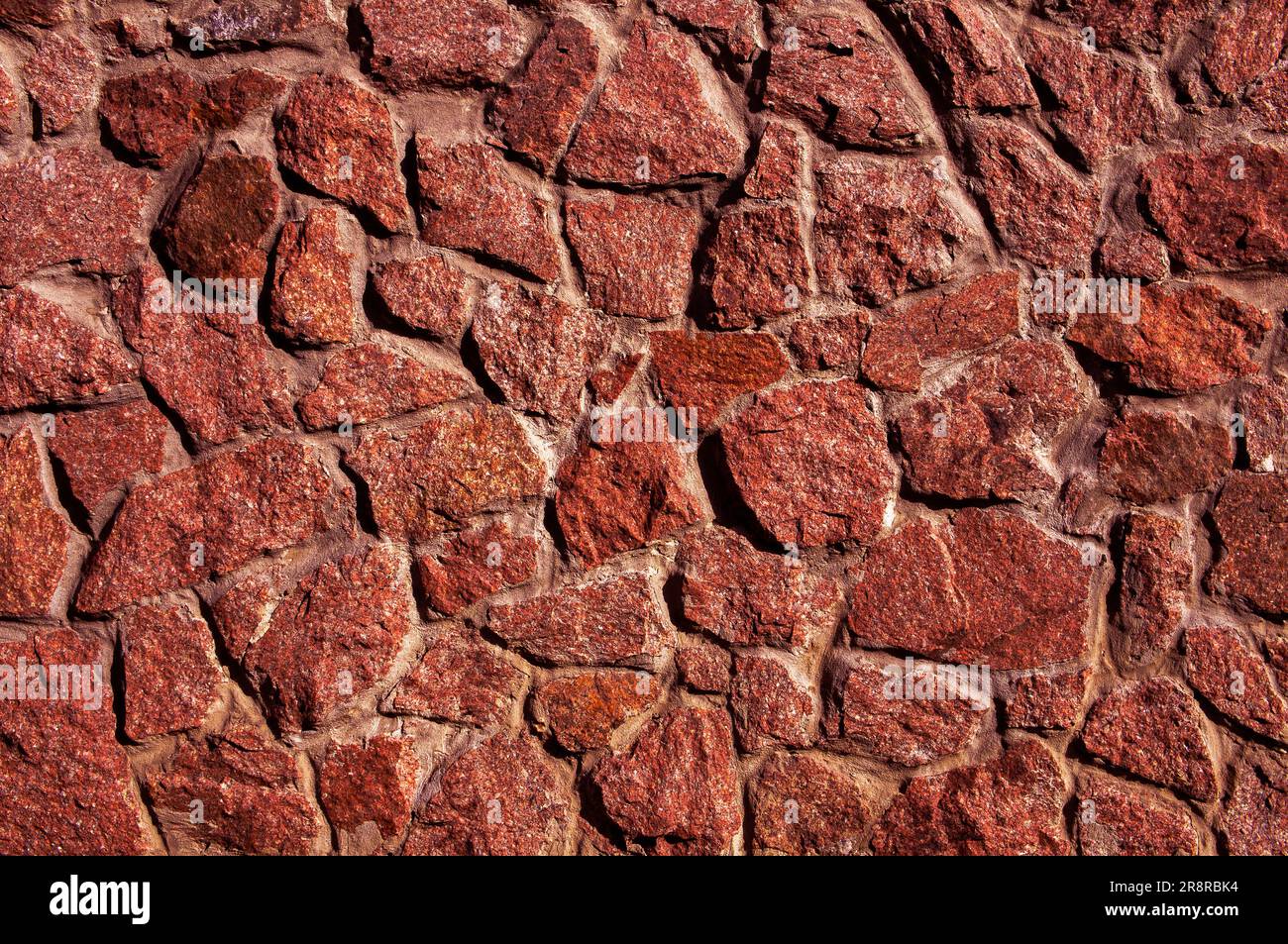 An old wall made of rough, red, hewn natural stones background Stock ...