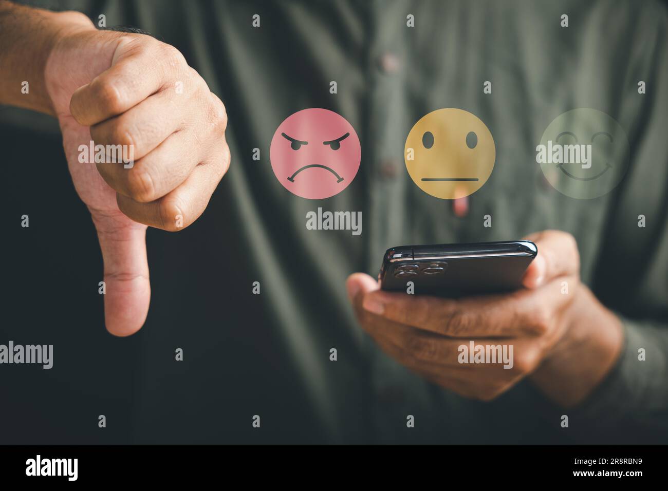 Unhappy client holding a mobile phone, displaying a thumb down sign ...