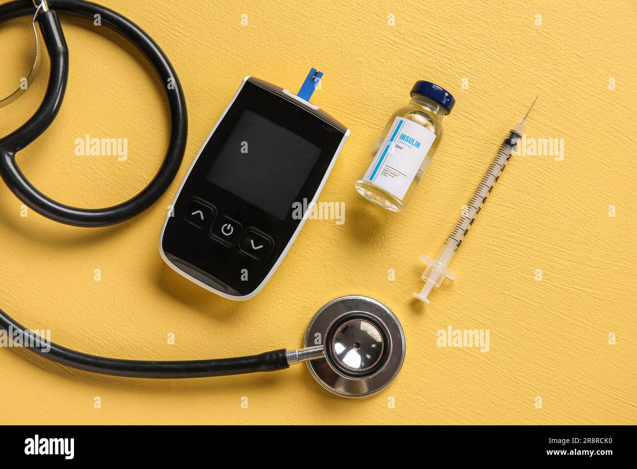 Glucometer with insulin, syringe and stethoscope on yellow background ...