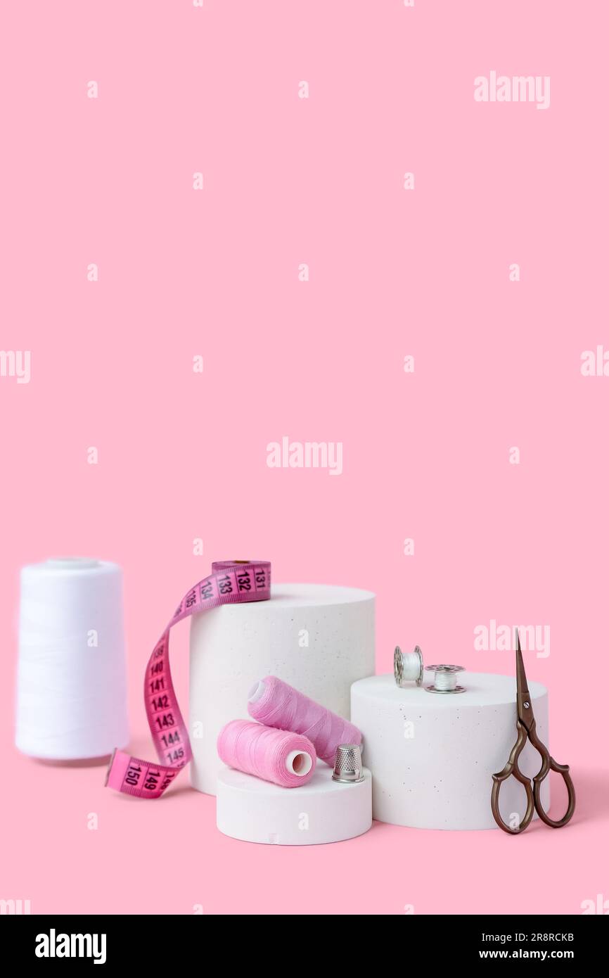 Podiums with tailor's supplies on pink background Stock Photo - Alamy