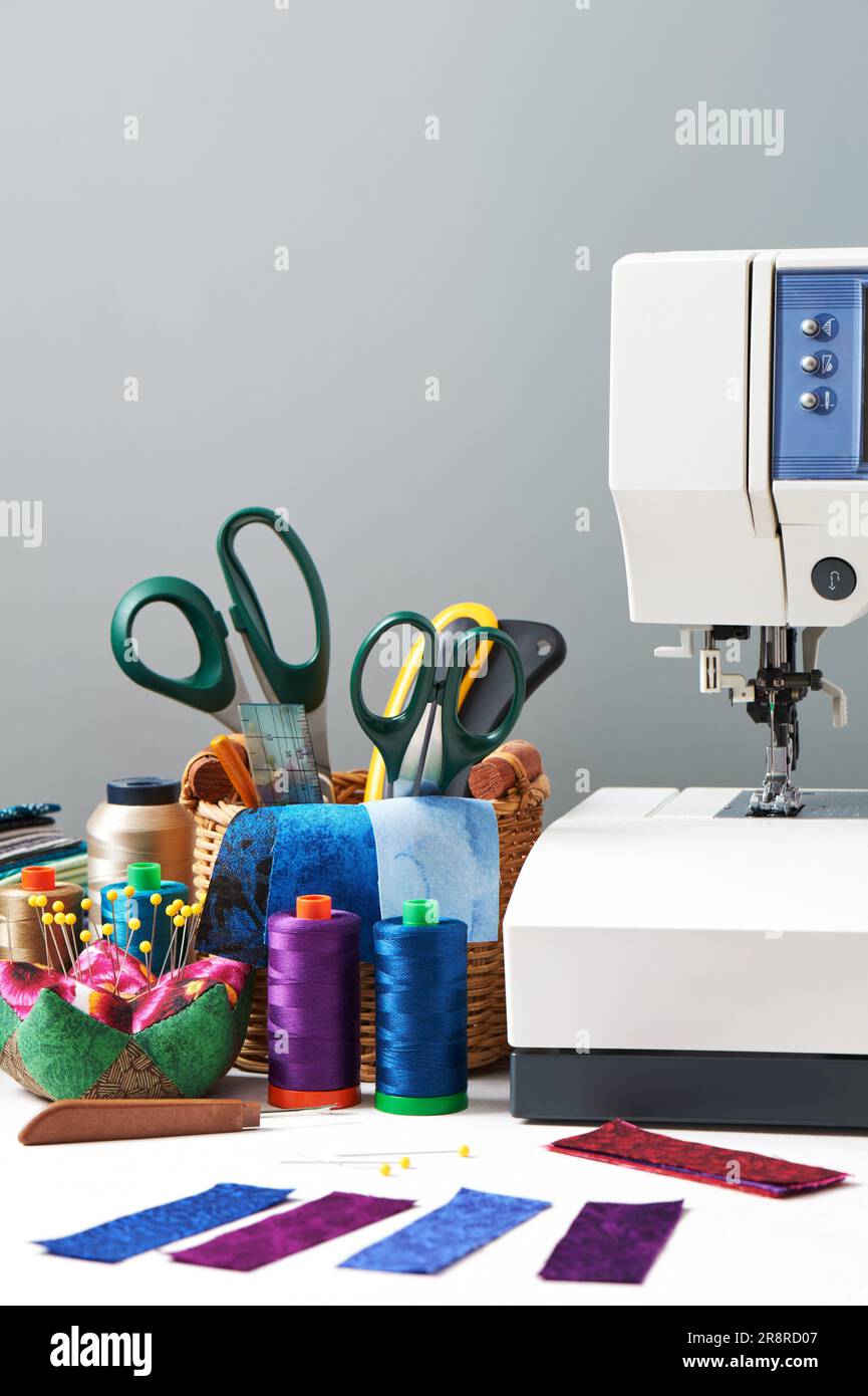 Sewing accessories in a basket and spools of threads next to sewing ...