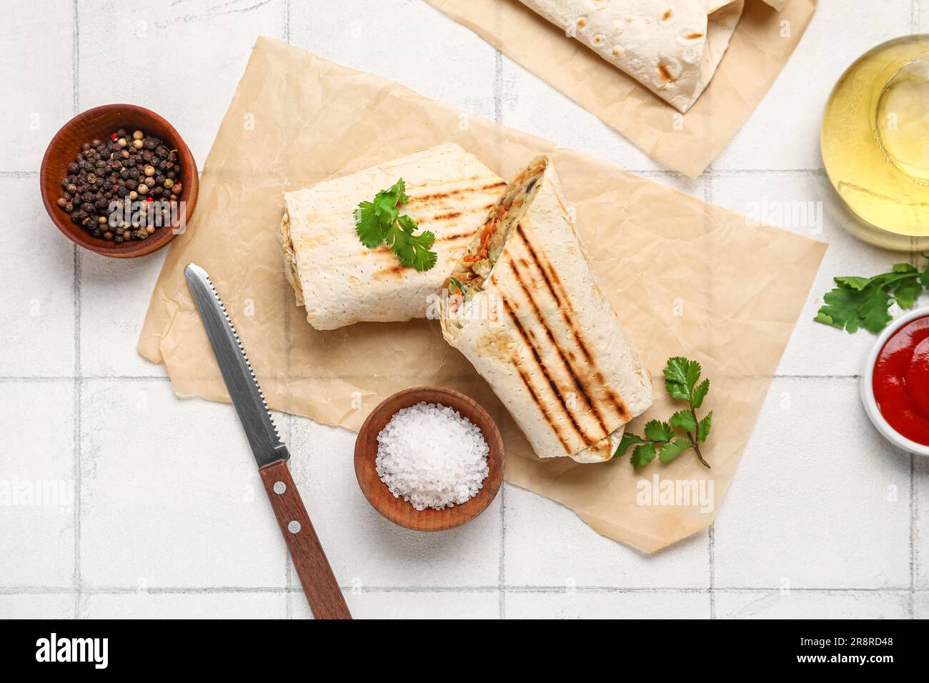 Baking paper with tasty shawarma with parsley on white tile table Stock ...