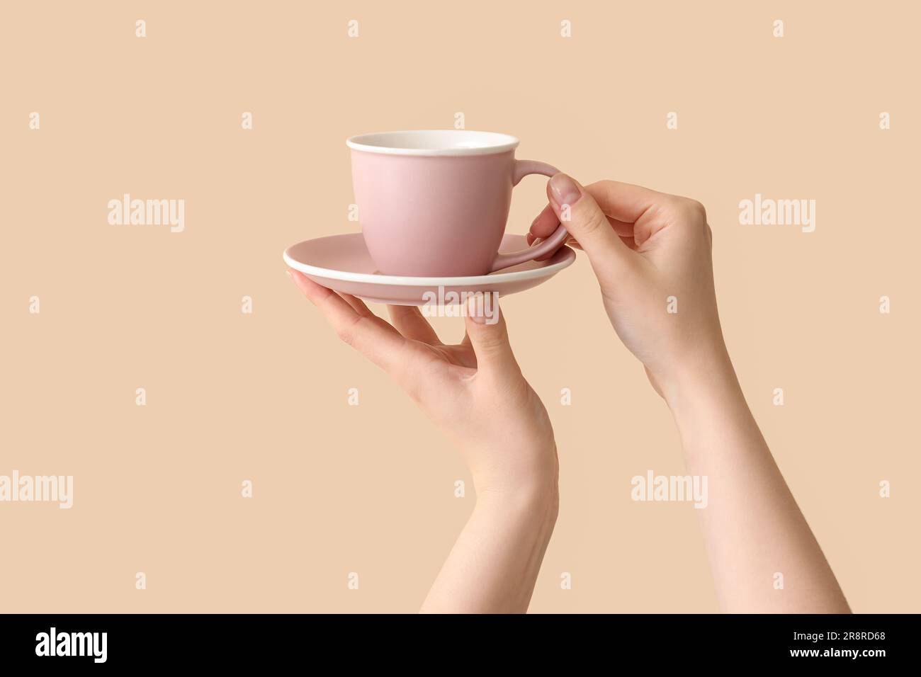 Female hands holding cup and saucer on beige background Stock Photo - Alamy