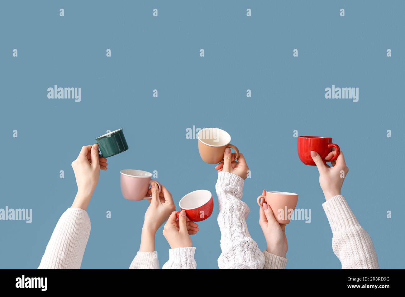 Female hands holding cups on blue background Stock Photo - Alamy