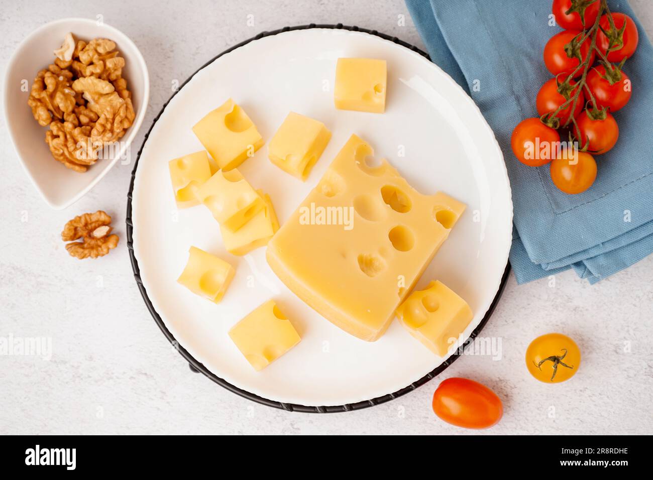 Stand and plate with pieces of Swiss cheese and tomatoes on white table ...
