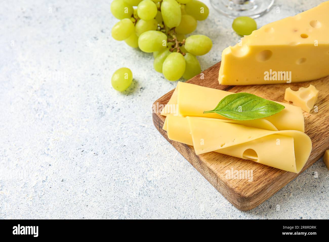 Wooden board with tasty Swiss cheese on light background Stock Photo ...
