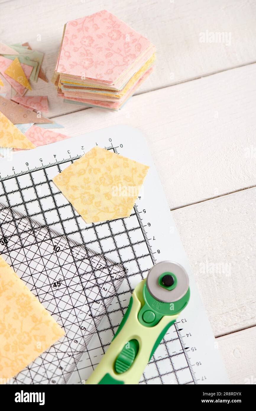 Fabric pentagon on craft mat next stack of pentagon pieces of fabrics ...