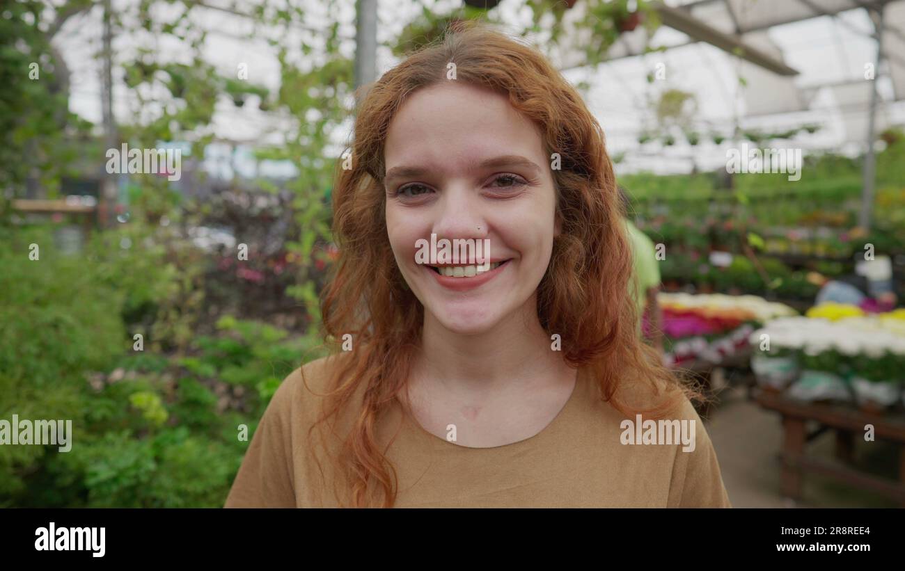 One happy young RedHead woman smiling at camera standing inside Flower ...
