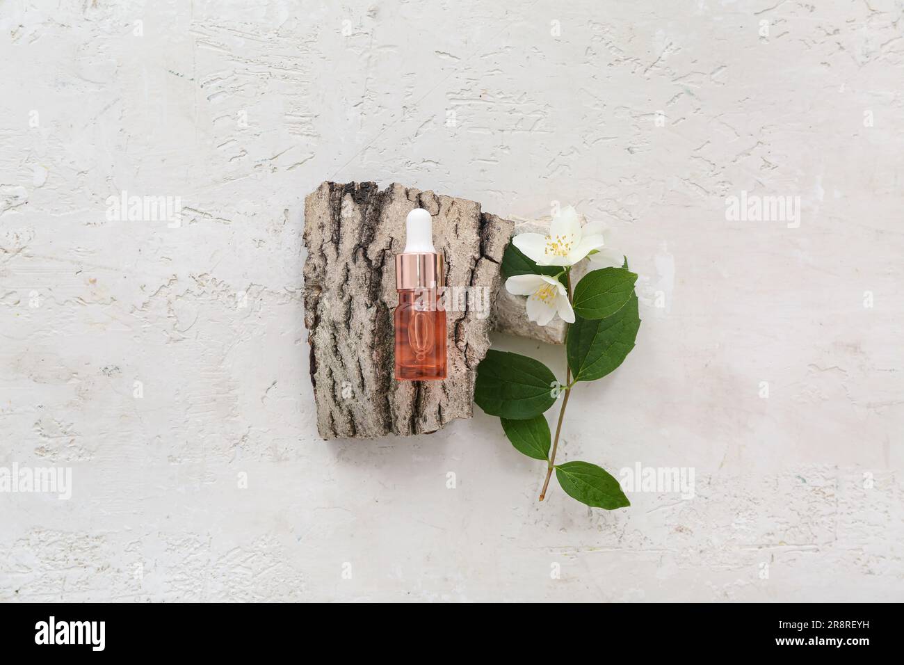 Bottle of cosmetic oil with jasmine flowers and tree bark on white ...