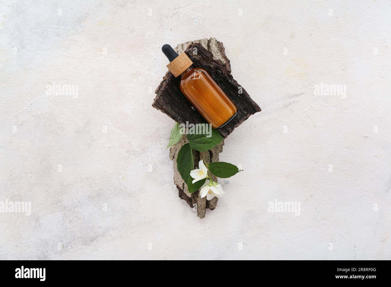 Bottle of cosmetic oil with jasmine flowers and tree bark on white ...