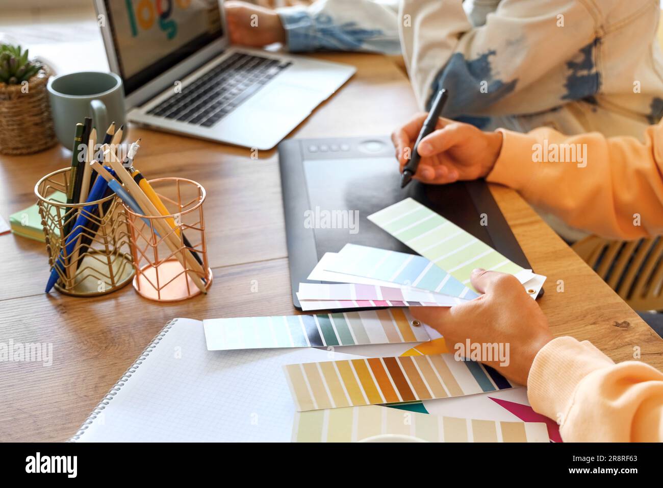 Male graphic designer working with tablet and color palettes at table ...
