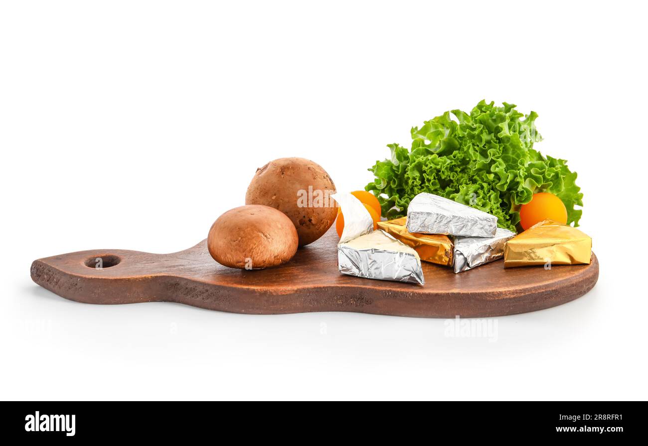 Board with triangles of tasty processed cheese in foil and vegetables ...