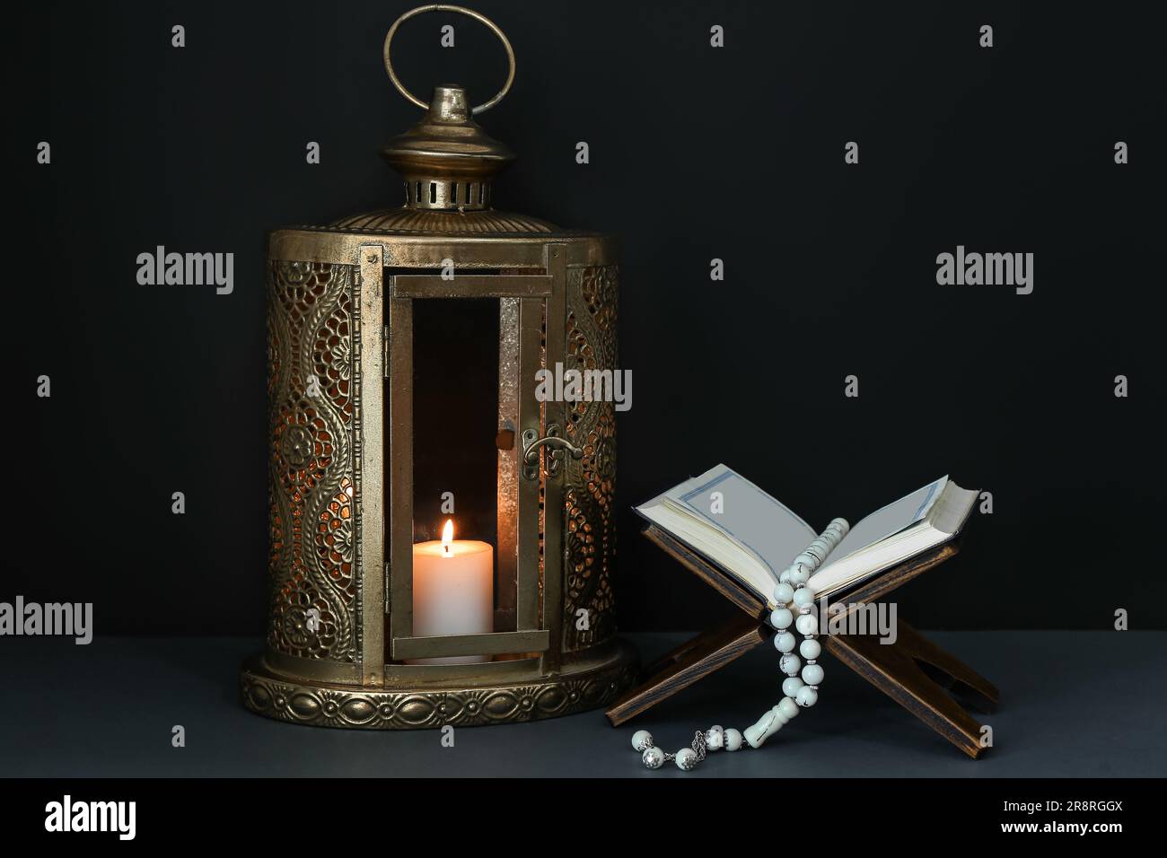 Fanous with burning candle, Koran and tasbih on dark background ...
