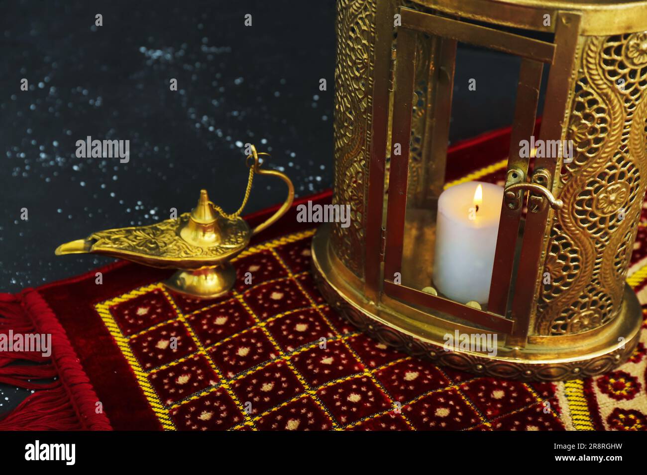 Fanous with burning candle, Aladdin lamp and prayer mat on dark ...
