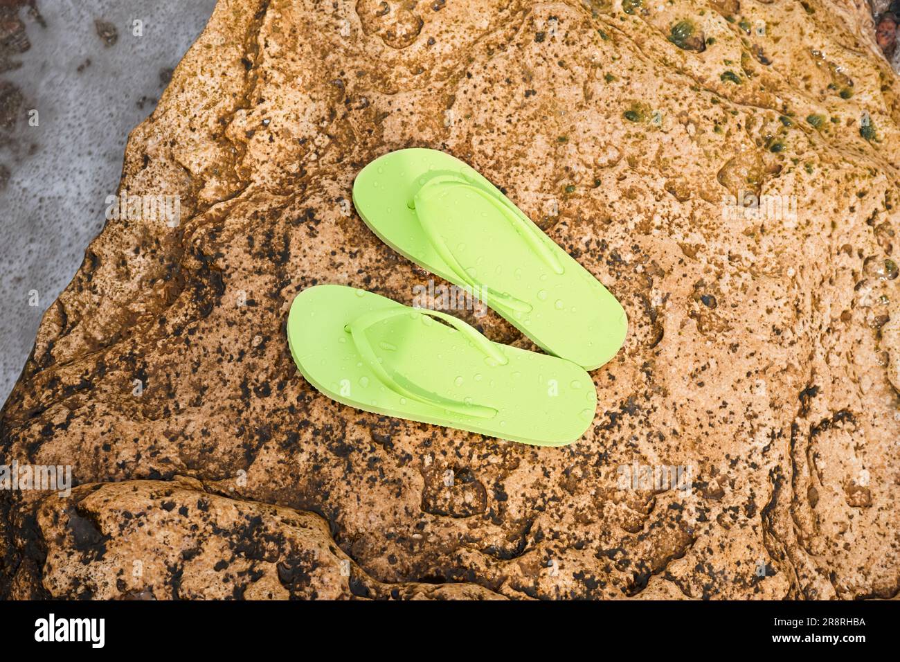 Green flip-flops on sea rock Stock Photo - Alamy