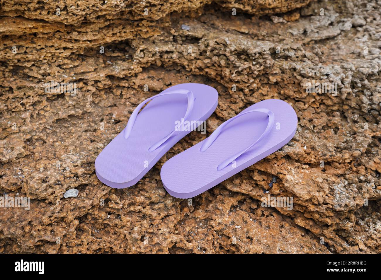 Stylish lilac flip-flops on rock Stock Photo - Alamy