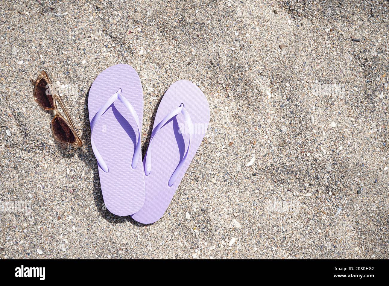 Lilac flip-flops with sunglasses on sand beach background Stock Photo ...