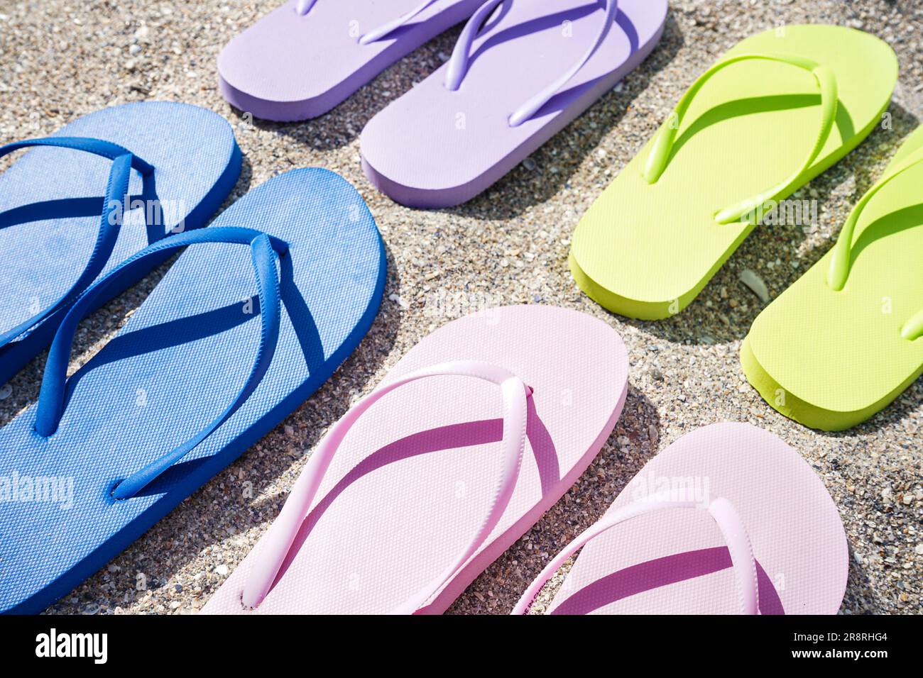 Different color flip-flops on sand beach background Stock Photo - Alamy