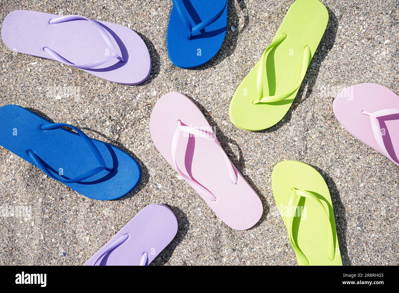 Different color flip-flops on sand beach background Stock Photo - Alamy