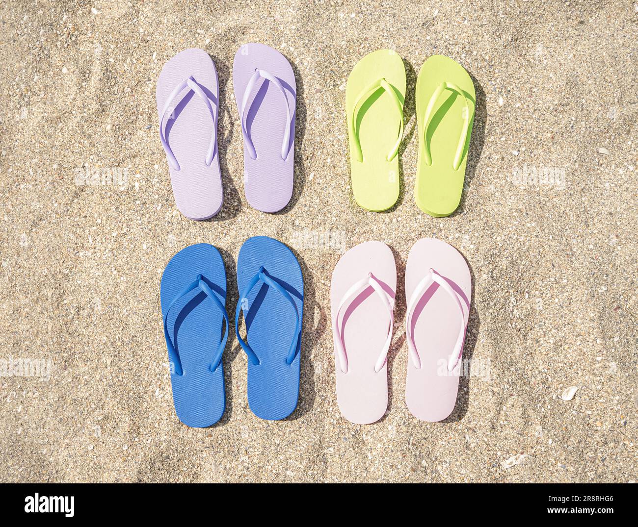 Different color flip-flops on sand beach background Stock Photo - Alamy