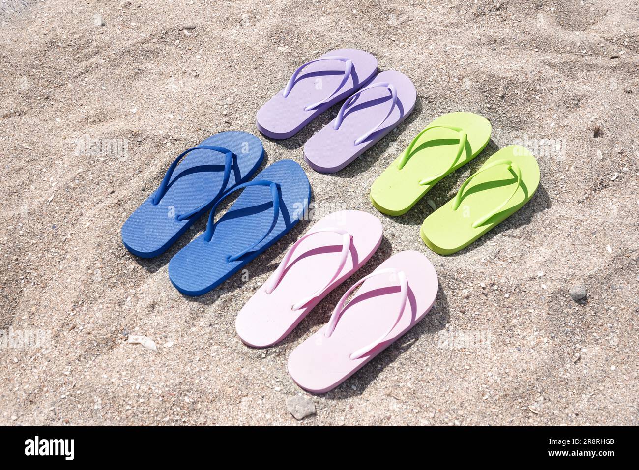 Different color flip-flops on sand beach background Stock Photo - Alamy