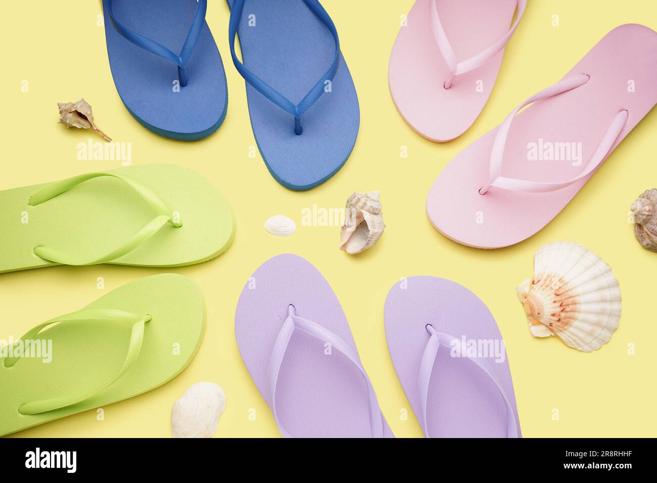 Different color flip-flops with shells on yellow background Stock Photo ...