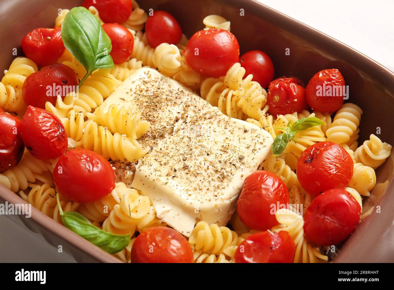 Baking dish of tasty pasta with tomatoes and feta cheese on white ...