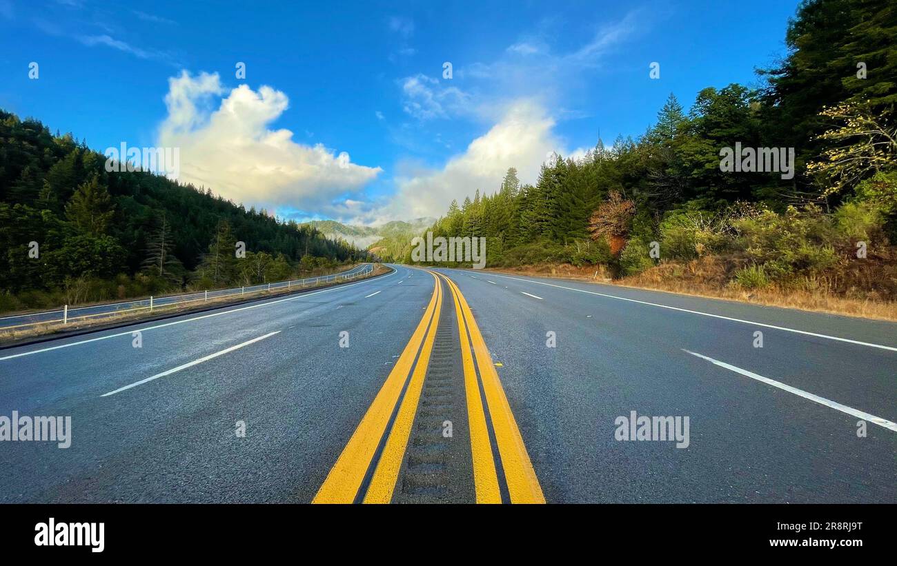 An aerial view of a long open highway with trees and shrubs lining the ...