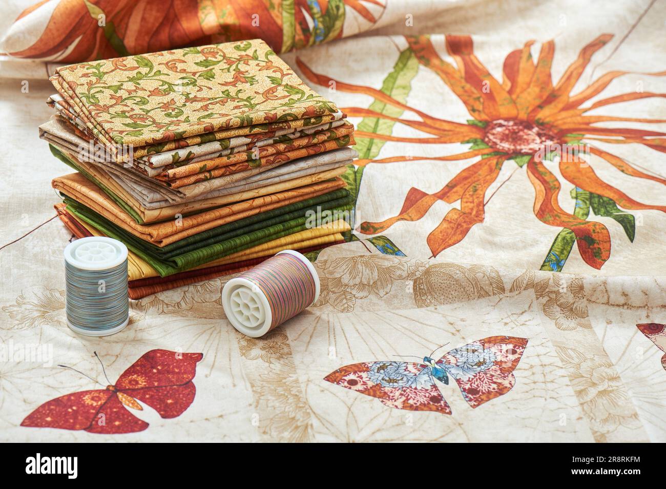 Heap of pieces quilting fabrics lay on cloth with flowers and butterfly ...