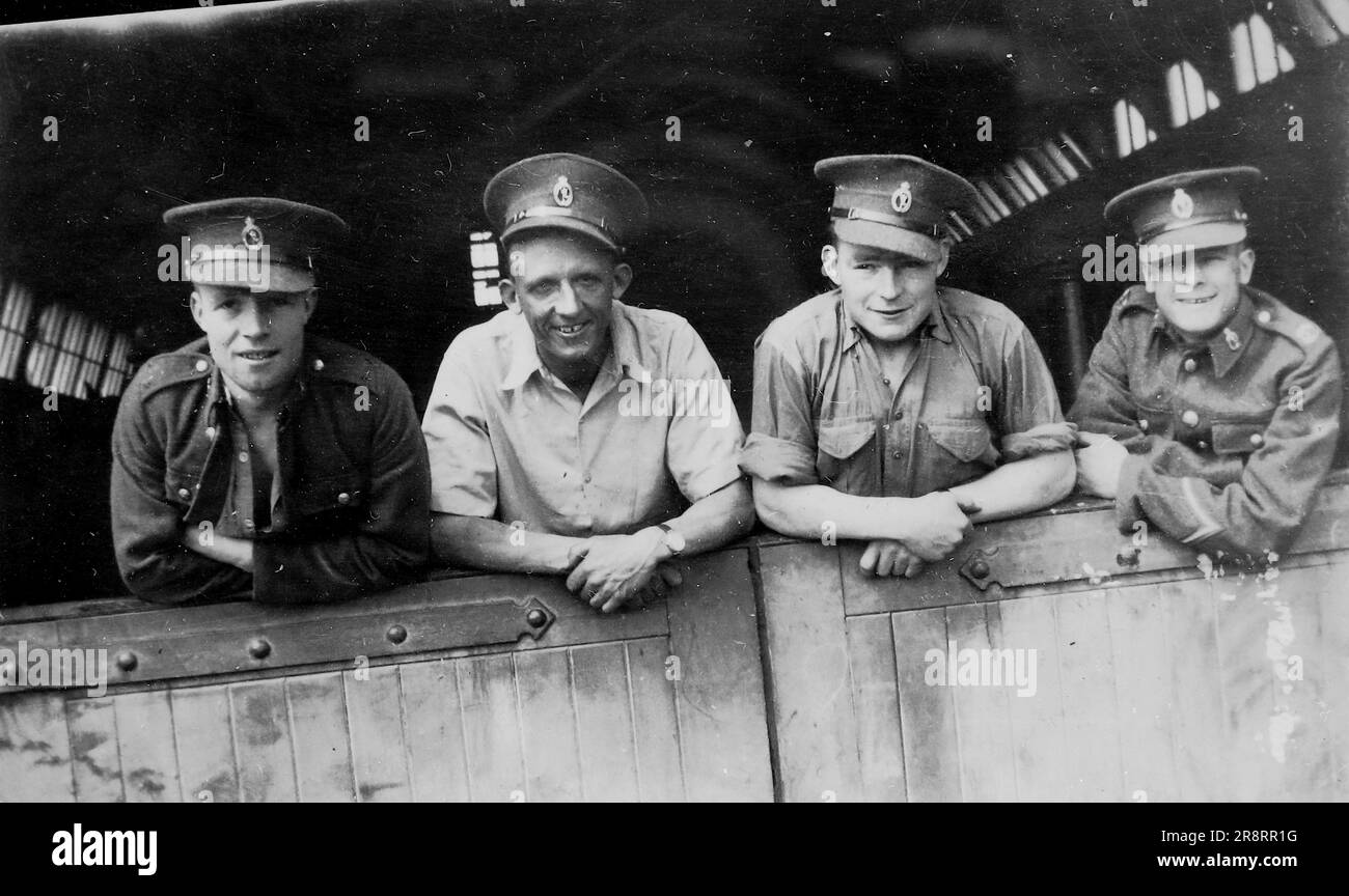 A group of four military men leaning on a wide gate, possibly a hangar ...