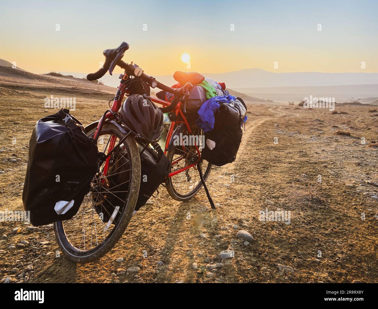 Loaded with bags red bicycle stands on side of road surrounded by ...