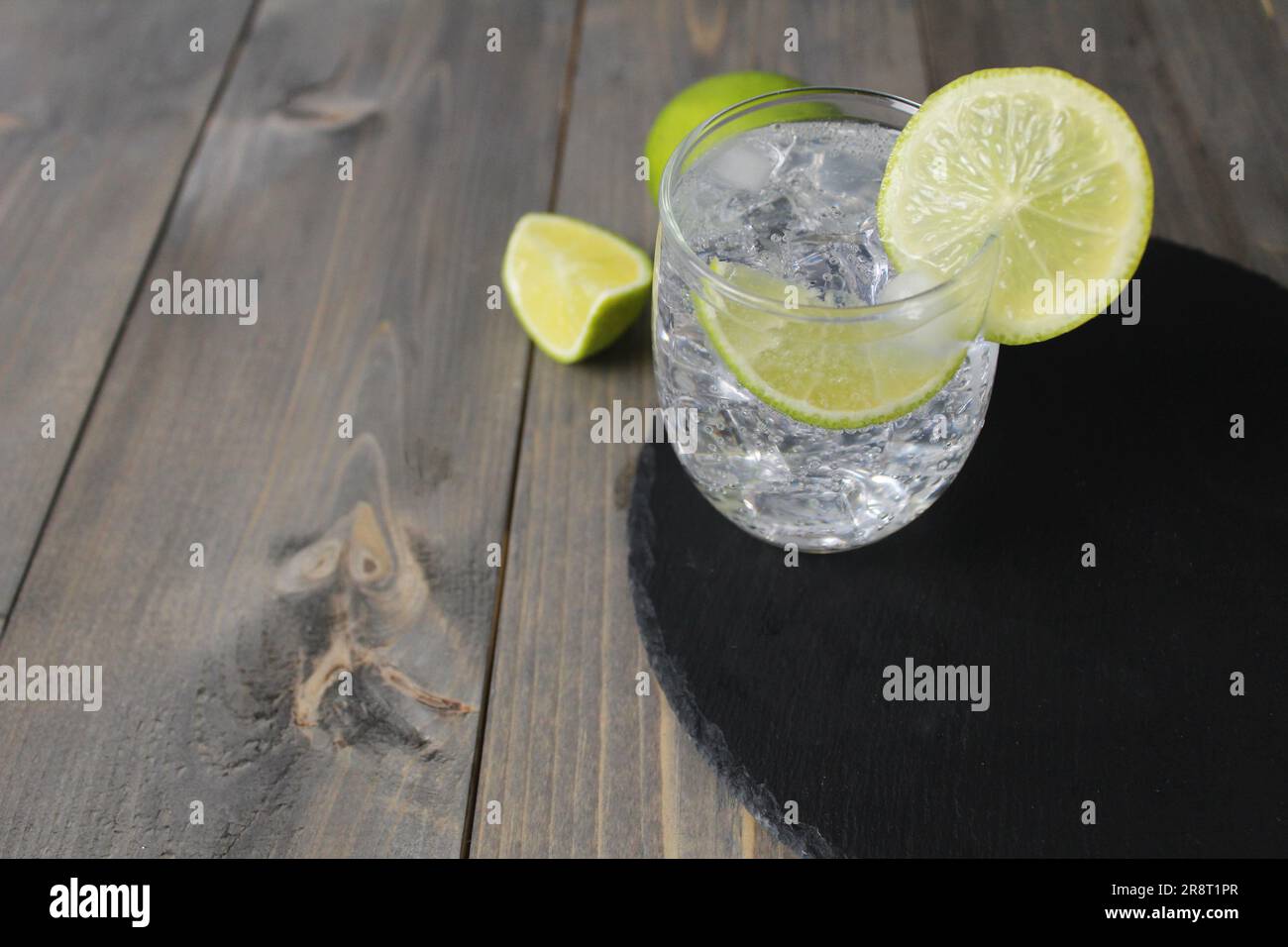 Lemonade soda with a slice of lime citrus in a glass with ice on a gray ...