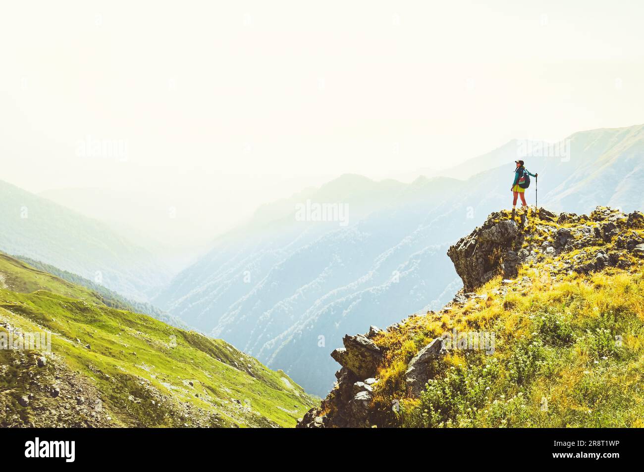 Back view fit sporty female hiker with nordic walk sticks stand on ...