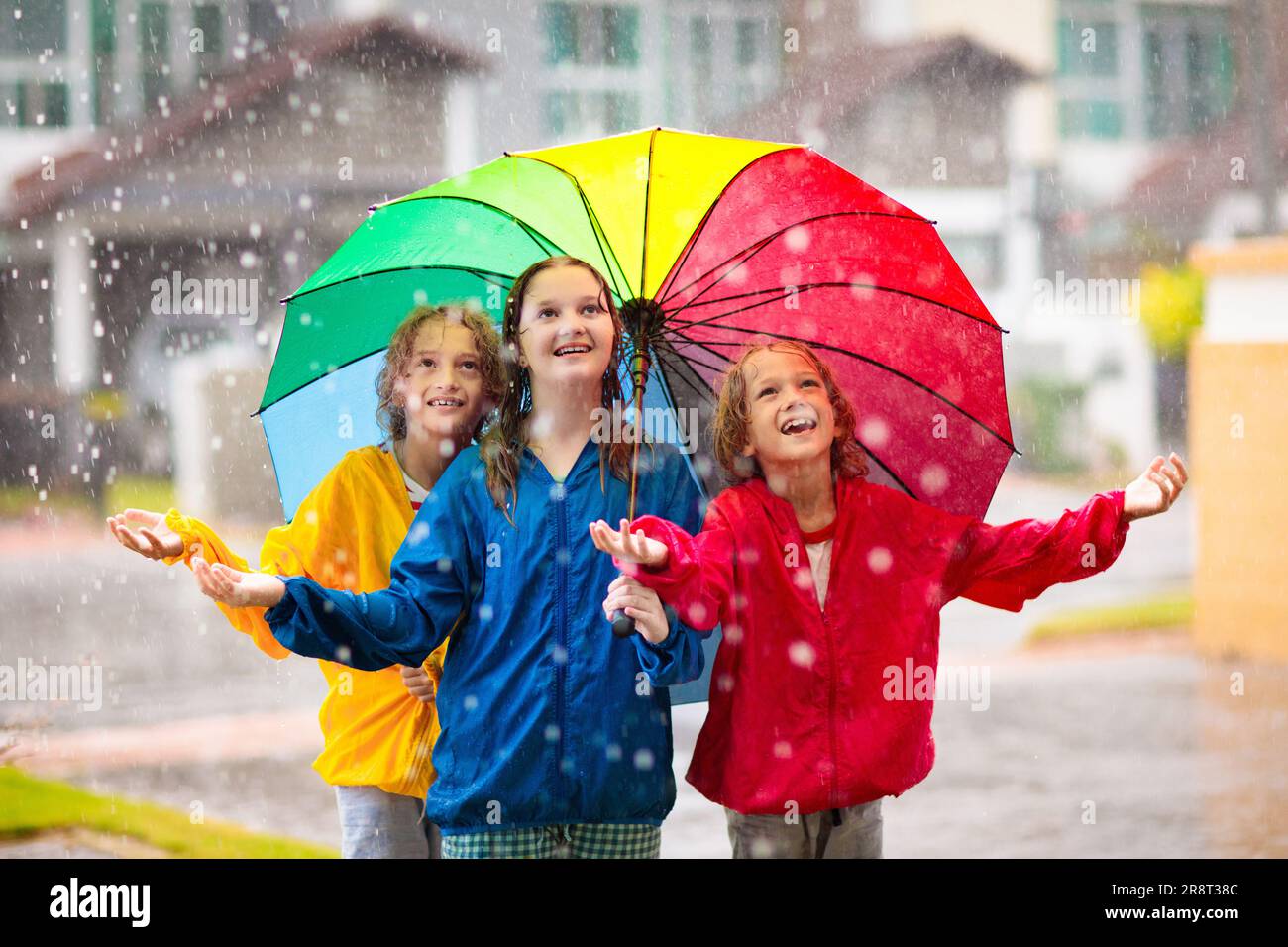 Kids play in heavy autumn rain. Children walk on city street in cold ...