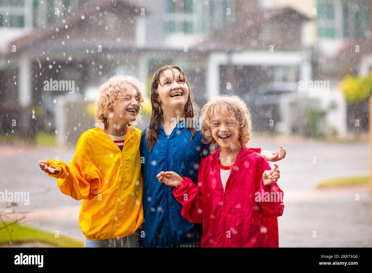Kids play in heavy autumn rain. Children walk on city street in cold ...