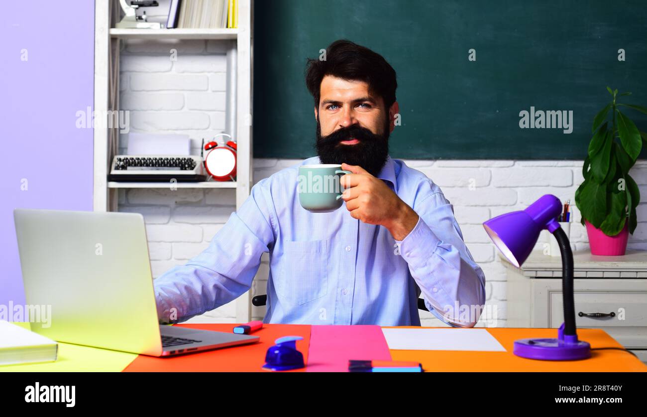 Male teacher drinking coffee in classroom. Smiling college teacher or ...