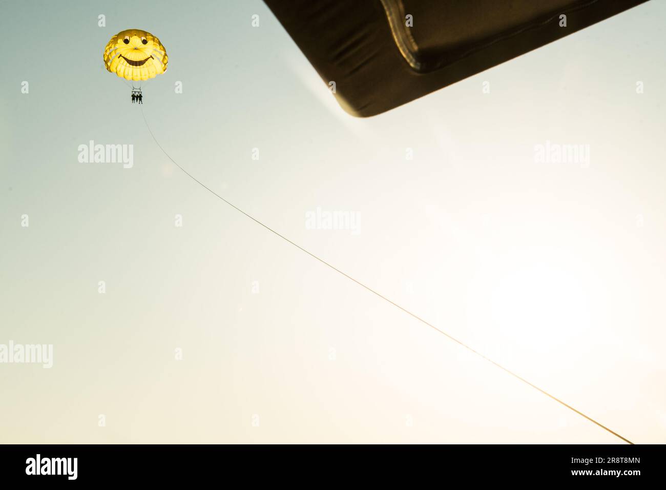 Three person family do para sailing in yellow parachute mid-air. Para ...