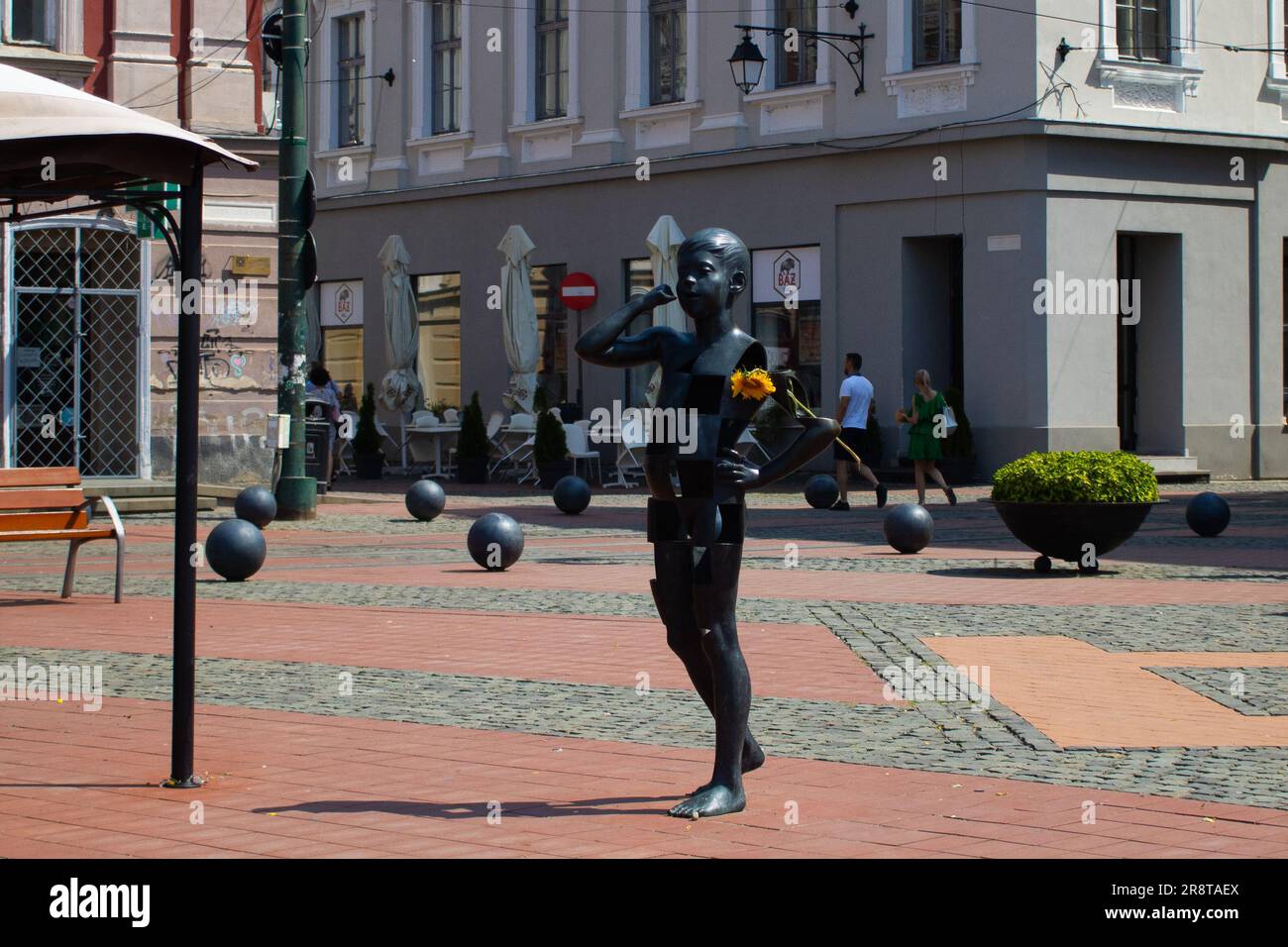 Boy talking on the phone and holding a yellow flower statue in the town ...