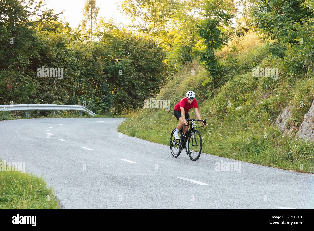 Professional female racing road cyclist riding very fast downhill and ...