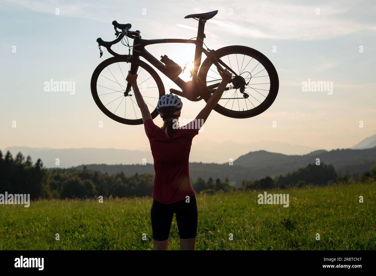 Female road cyclist raising bicycle with both arms above her head at ...