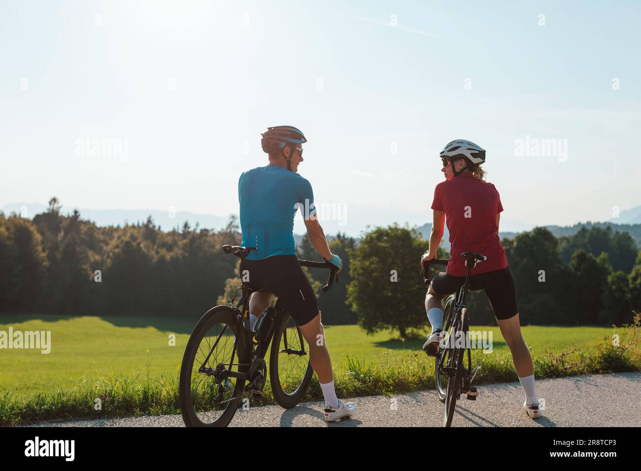 Professional Caucasian racing cyclists couple riding on an asphalt road ...