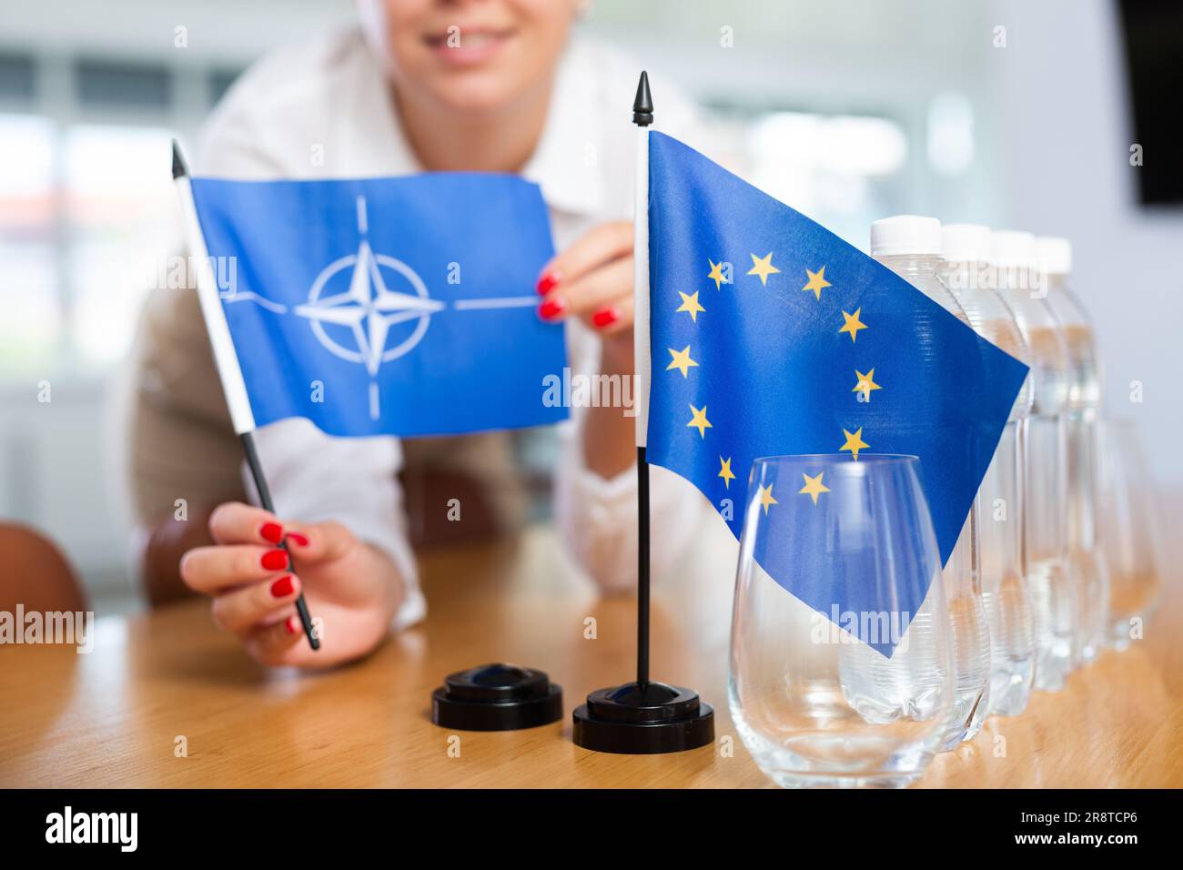 Female secretary places flags of the NATO (OTAN) and European Union ...