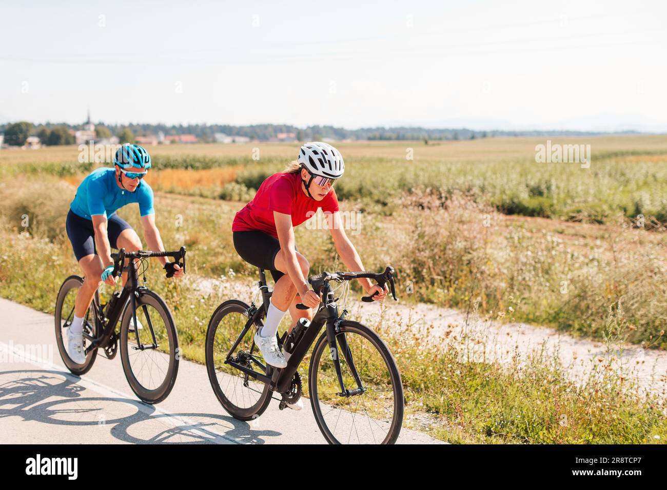 Two Caucasian athletes, female and male road racing cyclists, riding ...