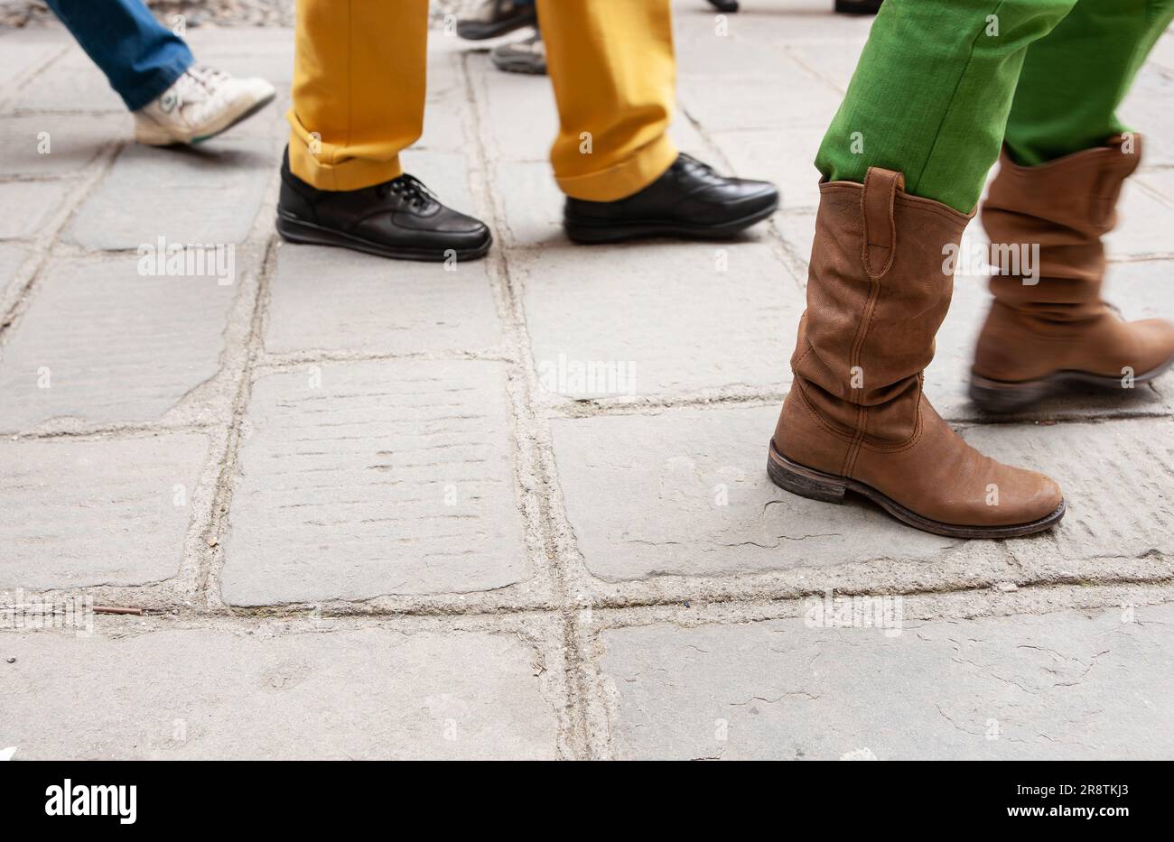 Focus on brown high boot with bright green trouser of people walking by ...