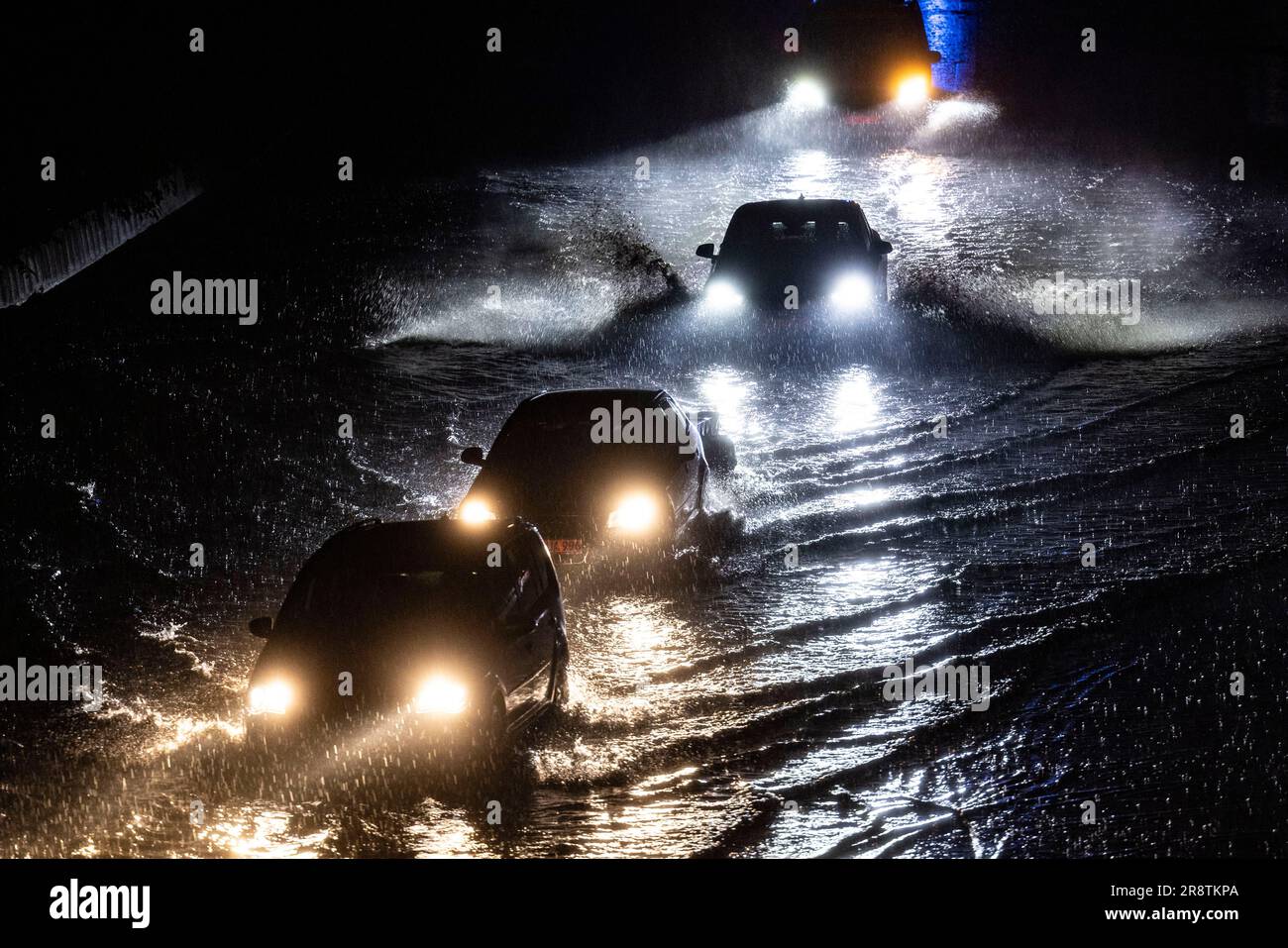 Vehicles drive through a flooded section of the A59 highway as heavy ...